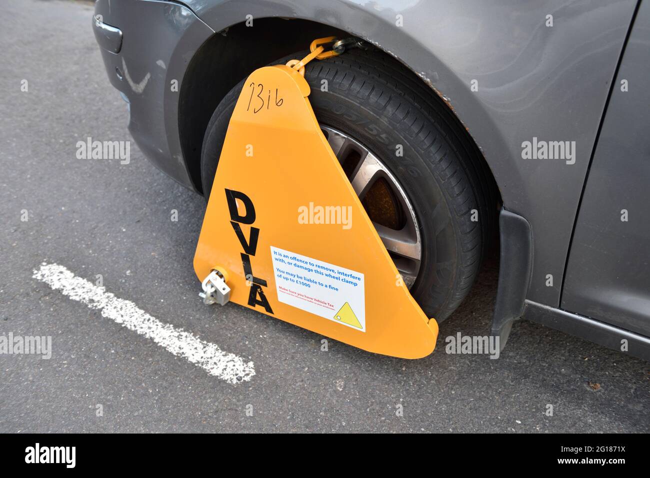 DVLA wheelclamp on front wheel of parked car, UK Stock Photo - Alamy