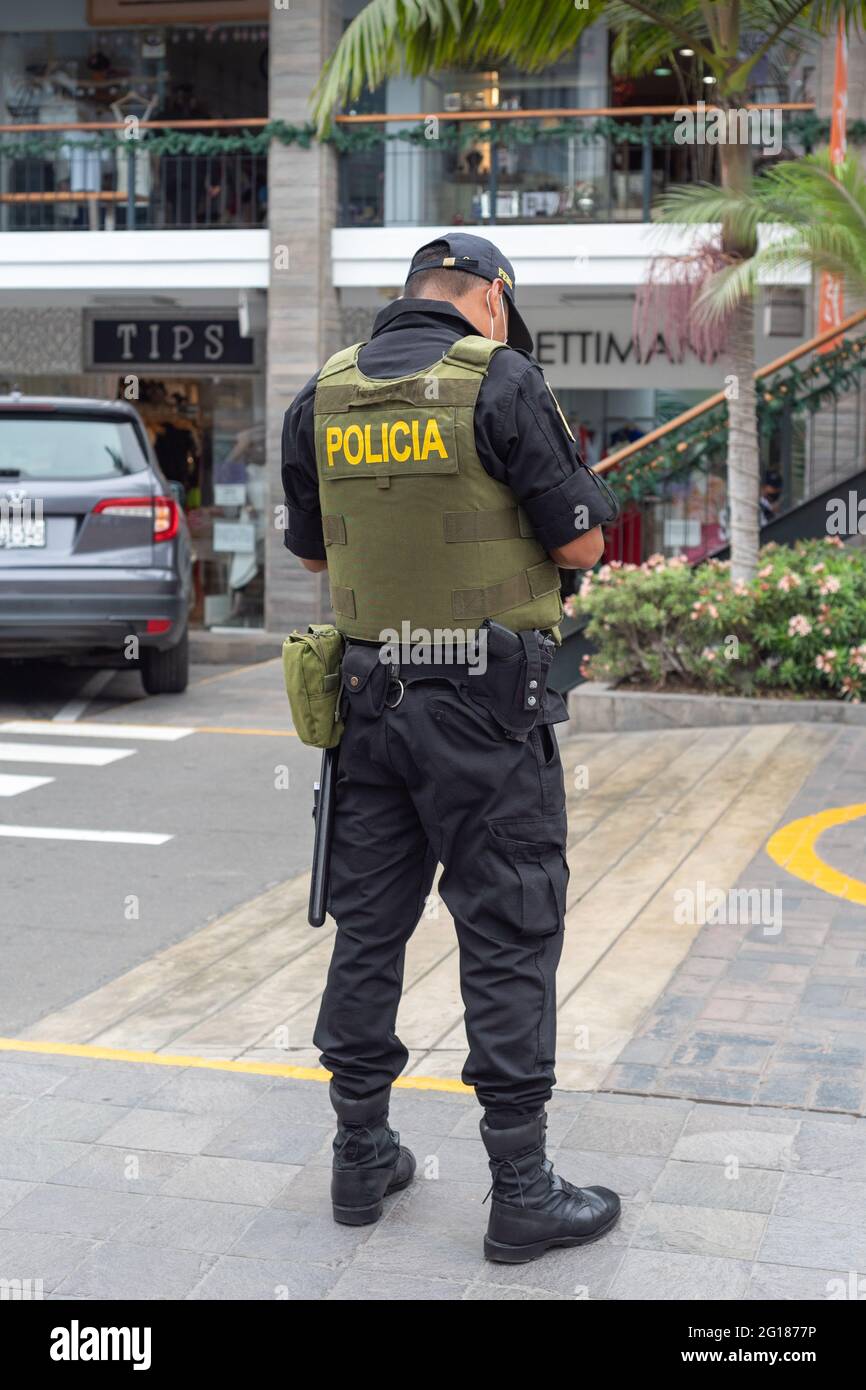 Back view of a peruvian policeman looking at his mobile phone in an ...