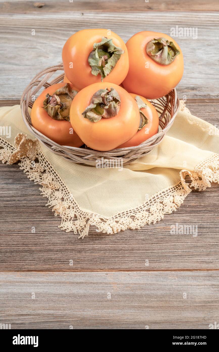 ripe persimmon fruits in a basket on wooden table with copy space Stock ...