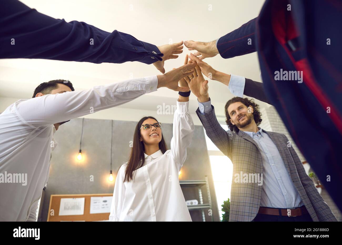 Diverse business team joining hands together standing in office view ...