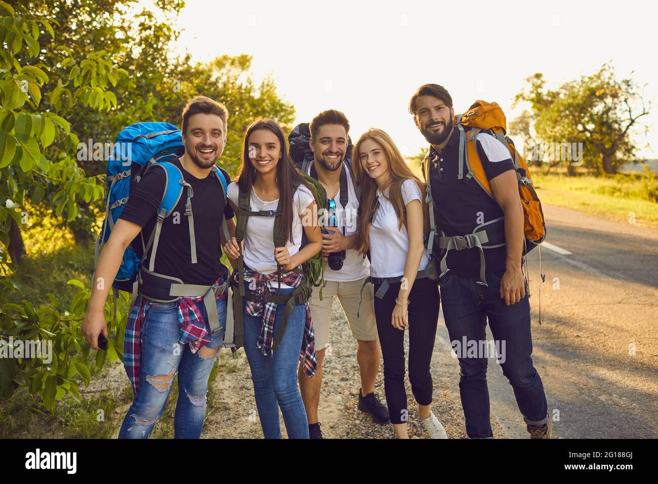 Group of young tourists hikers standing and looking at camera together ...