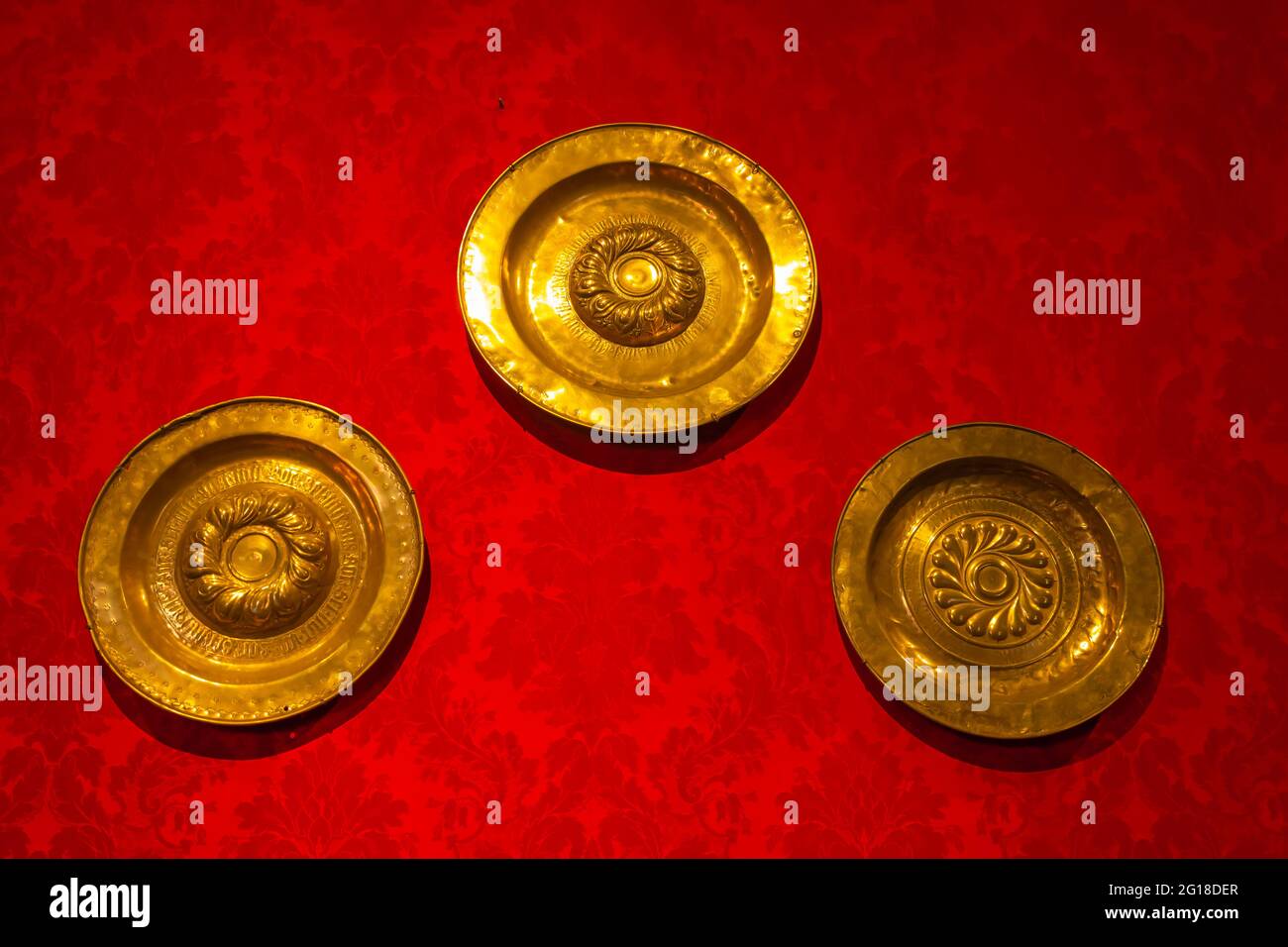 Three golden plates on a red background Stock Photo - Alamy