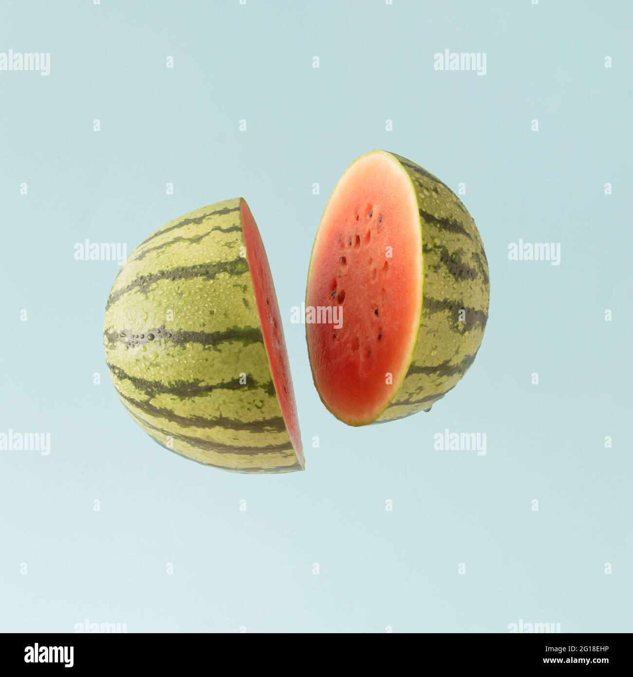 Watermelon fruit cut into two parts with water droplets on a blue ...
