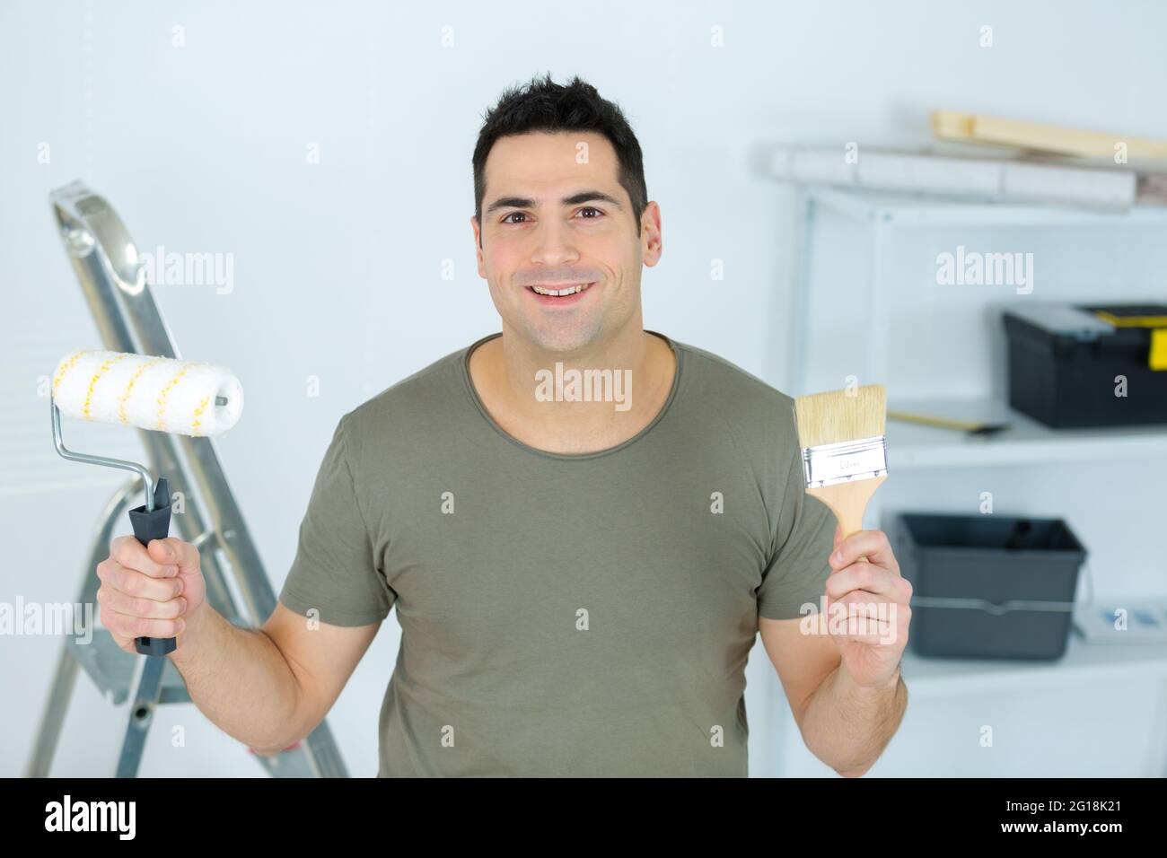 man holding paint rollers and brush Stock Photo - Alamy