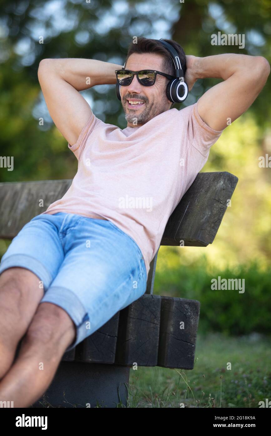 relaxed man listening music using headphones outdoors on bench Stock ...
