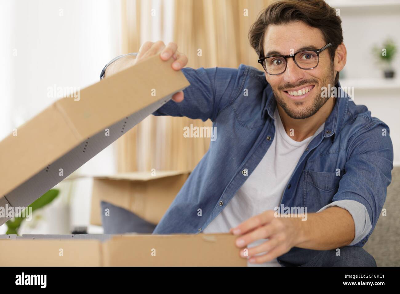 contented man opening a cardboard box Stock Photo - Alamy