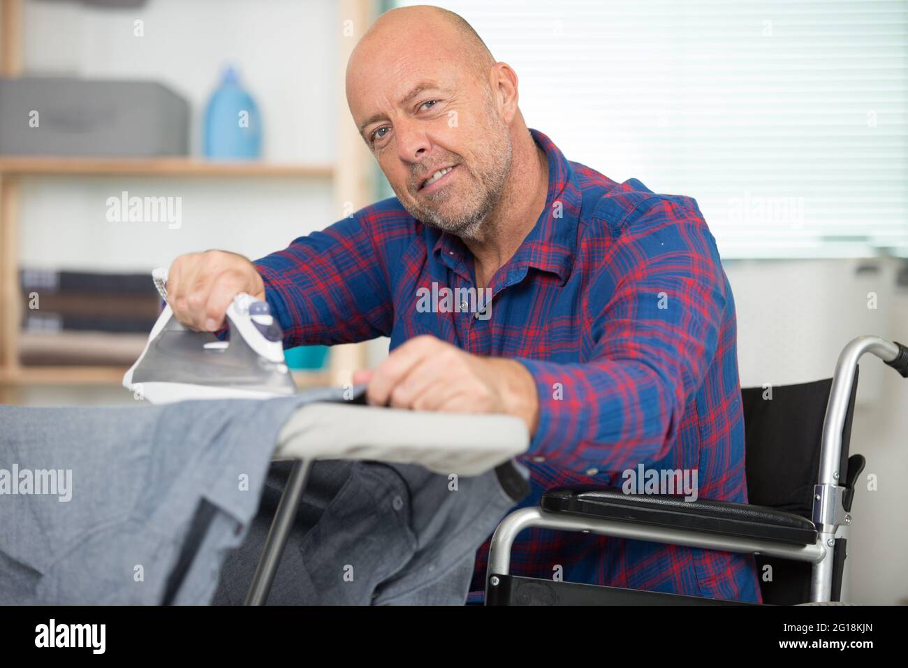 happy disabled man on wheelchair ironing clothing Stock Photo - Alamy