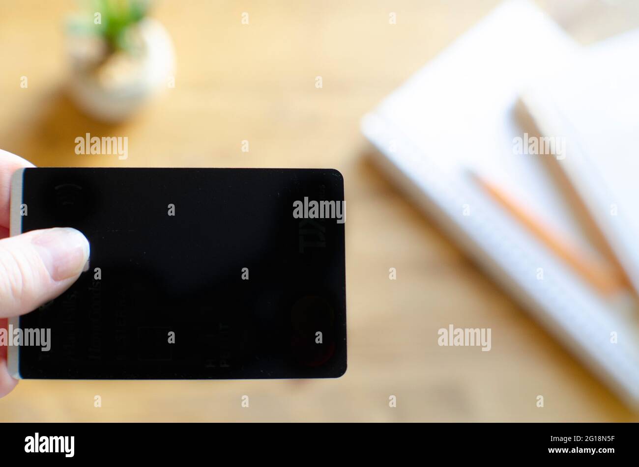 Hand holding black blank credit card with notepad in background Stock ...