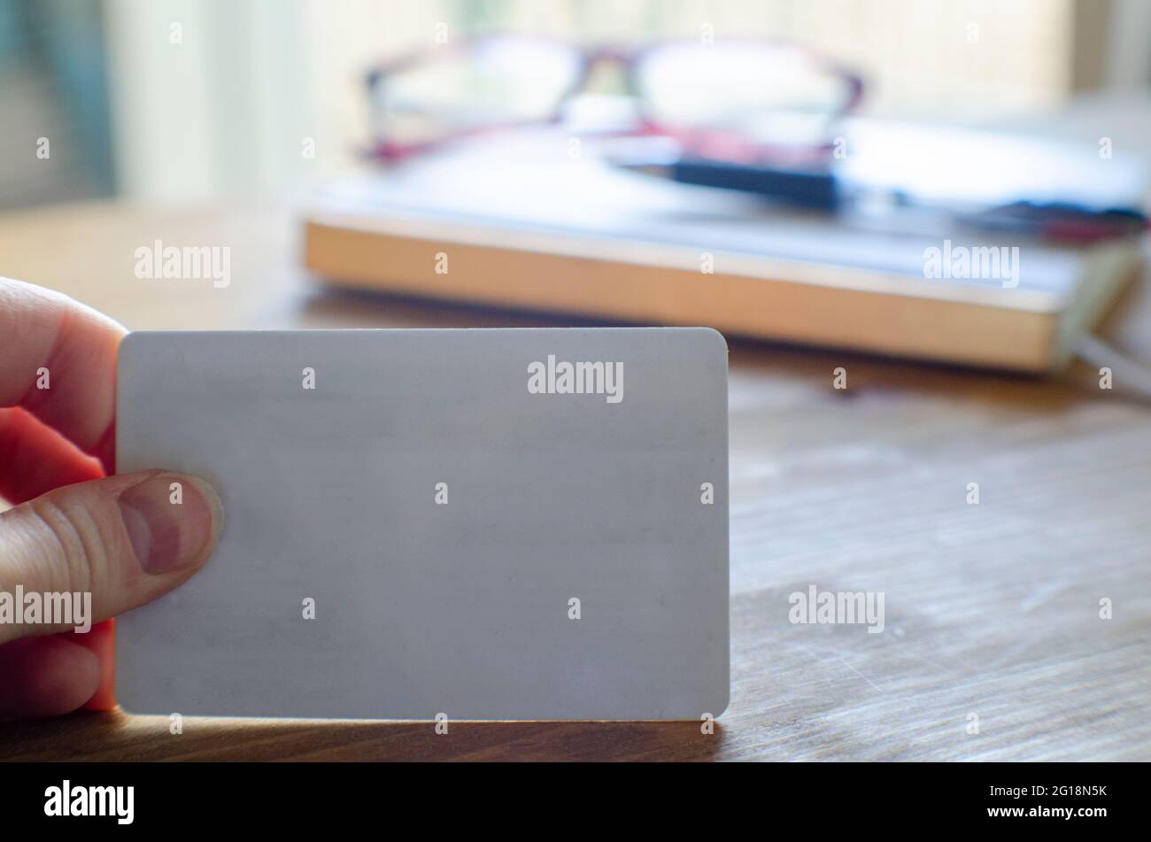 Hand holding blank white insurance card with glasses and notebook in ...