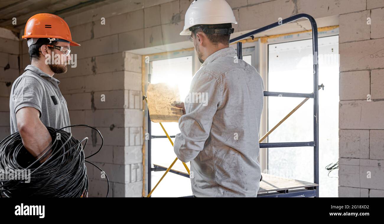 Two builder engineers talking at a building site, engineer explaining a ...