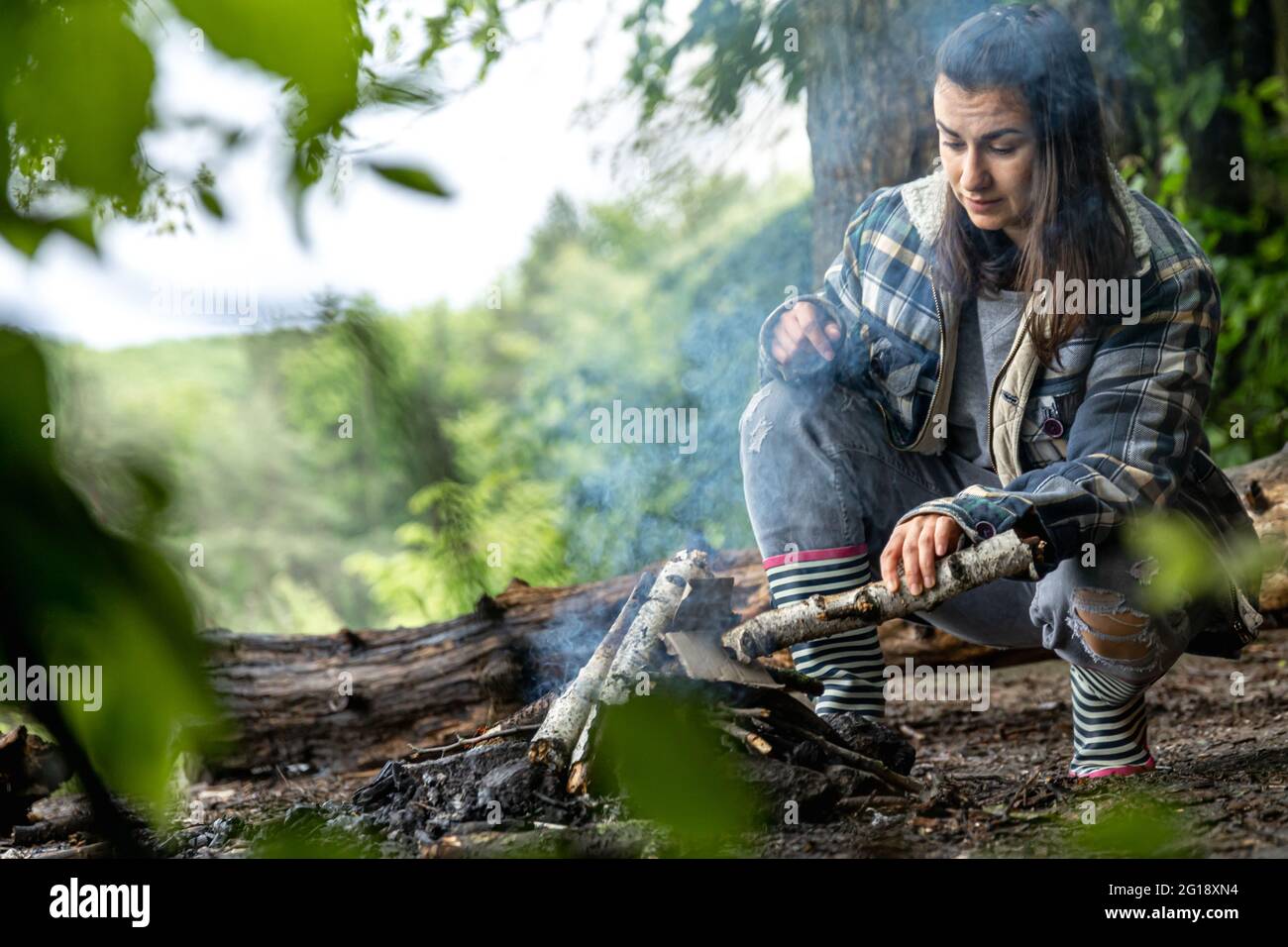 An attractive young woman makes a fire to keep warm in the forest Stock ...