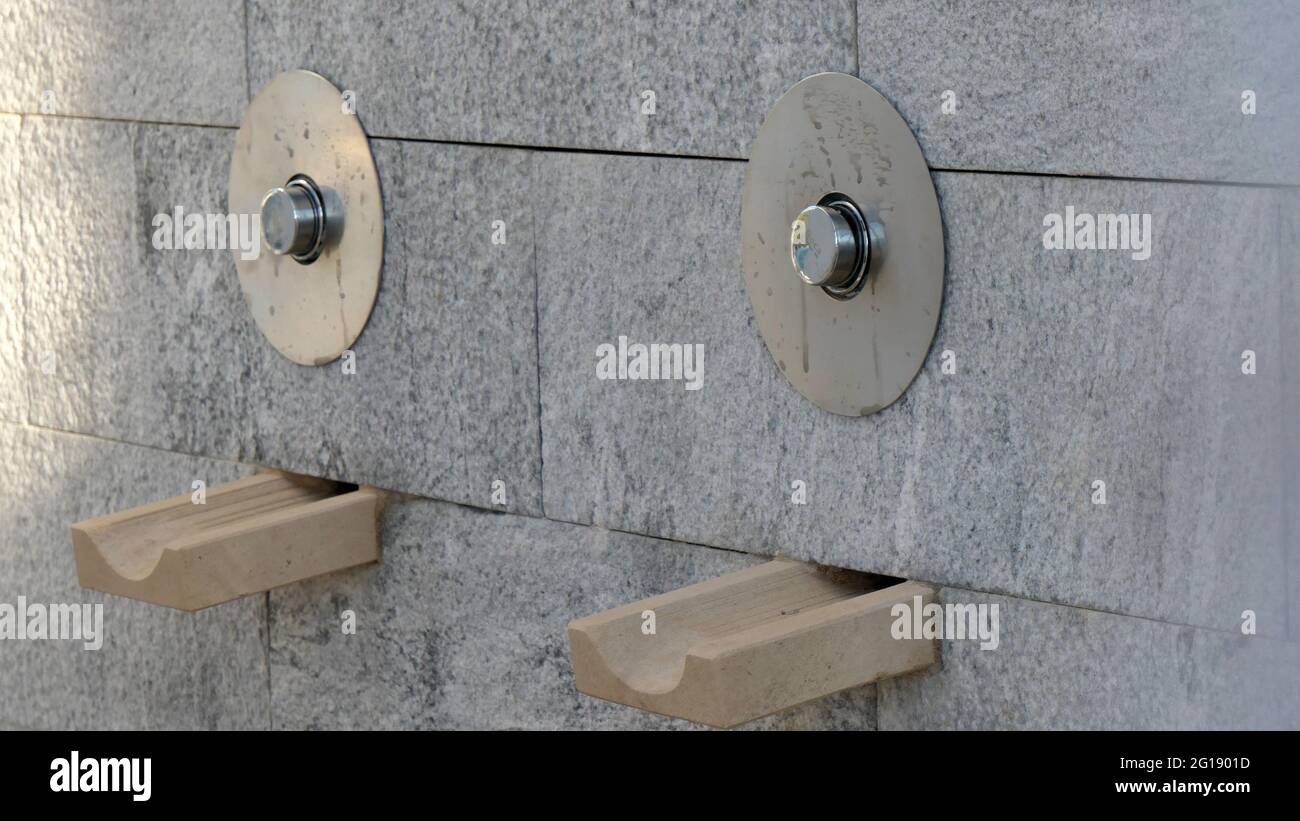 Push taps and drainage set in tiled wall in public convenience Stock ...