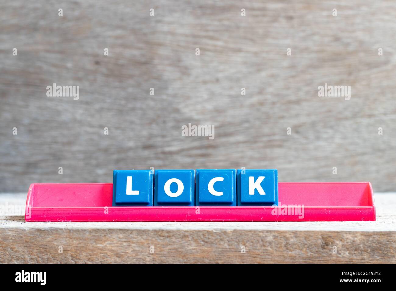 Tile letter on red rack in word lock on wood background Stock Photo - Alamy