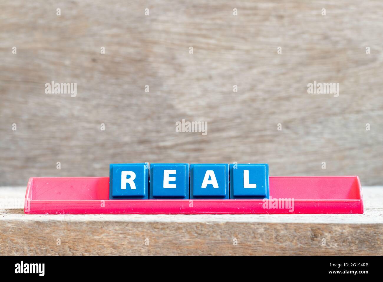 Tile letter on red rack in word real on wood background Stock Photo - Alamy