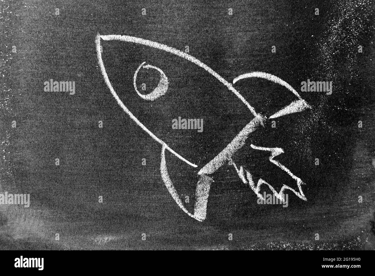 White color chalk hand drawing in rocket shape on blackboard or ...