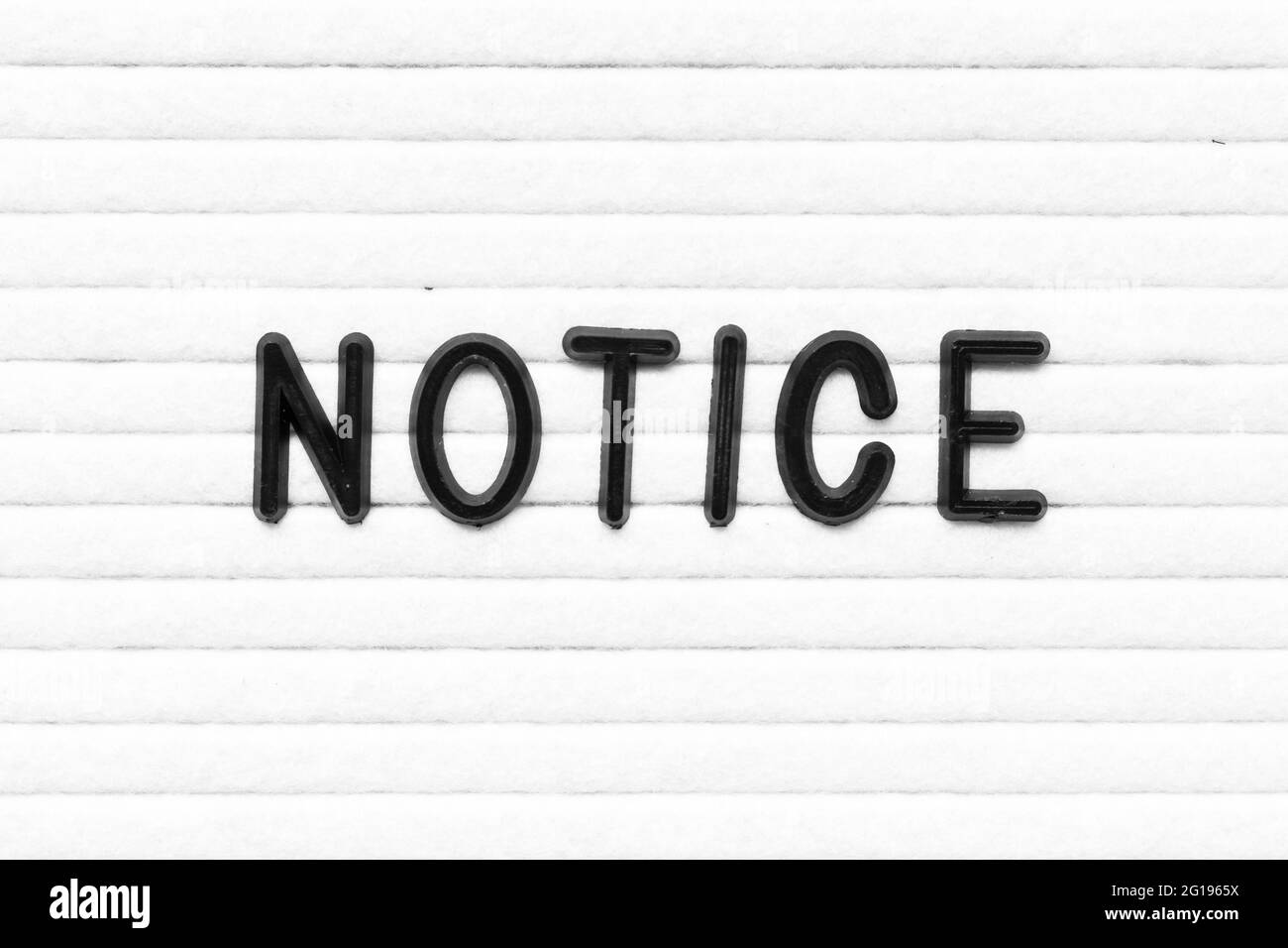 Black alphabet letter in word notice on white felt board background ...
