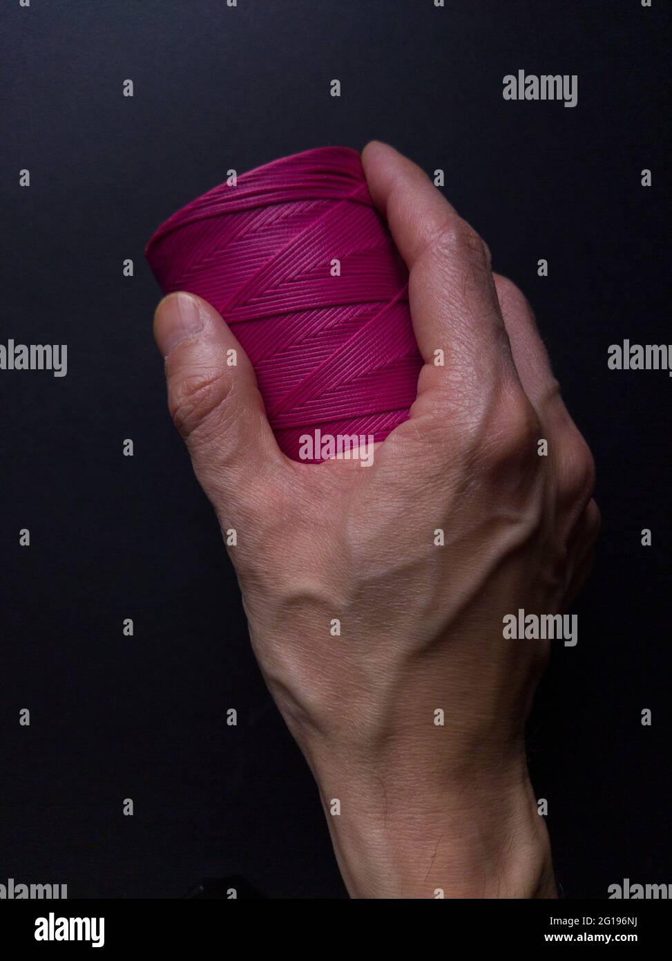A vertical top view of a pink sewing thread on a person's hand Stock ...