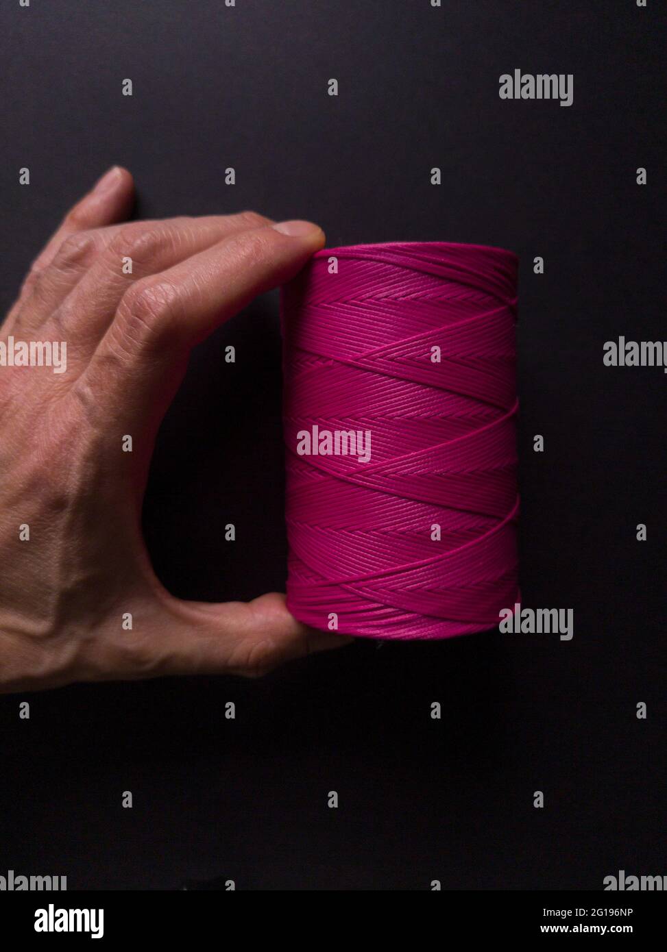 A vertical top view of a pink sewing thread on a person's hand Stock ...
