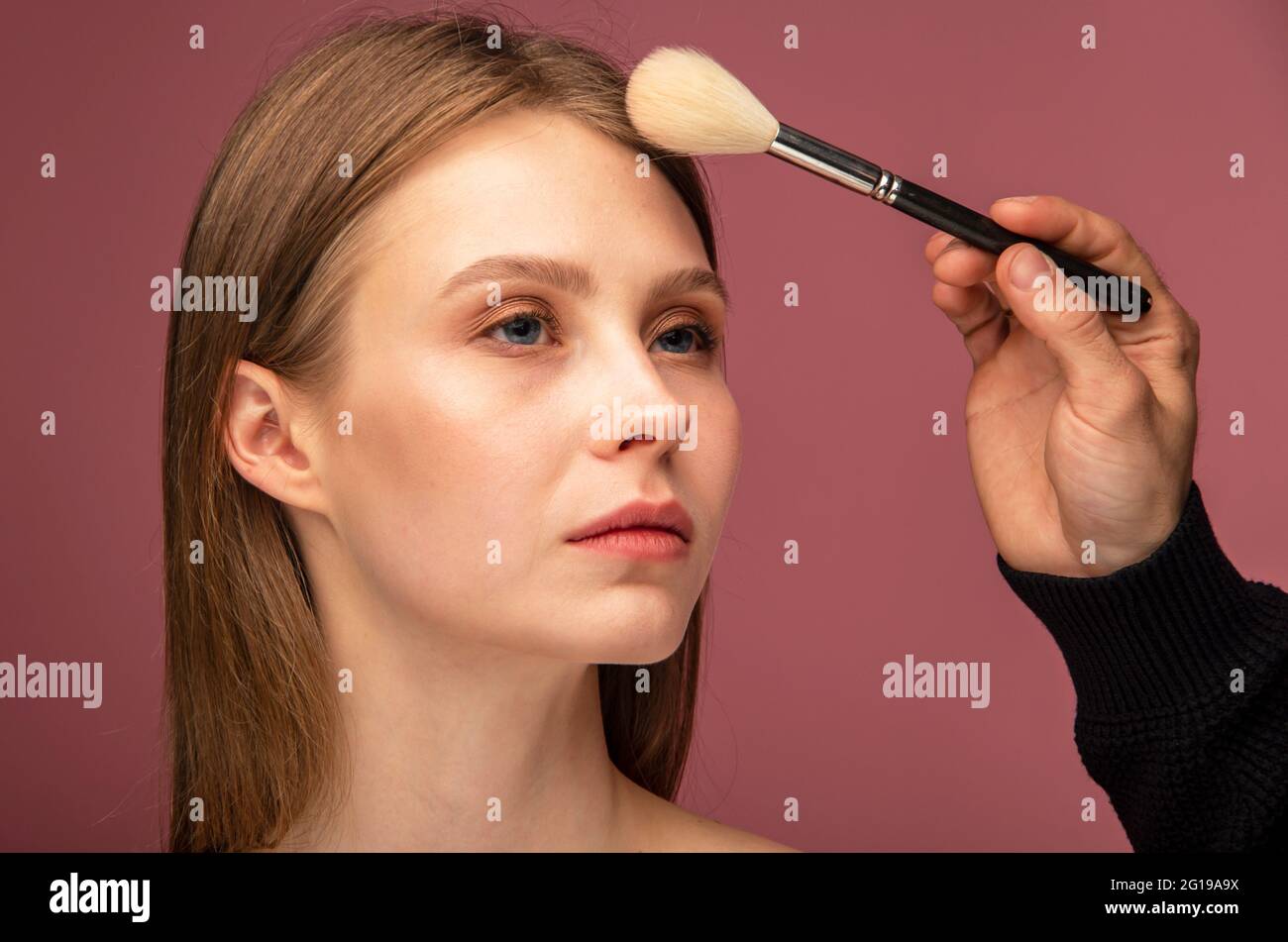 Beautiful young woman applying foundation powder. Make up artist is ...