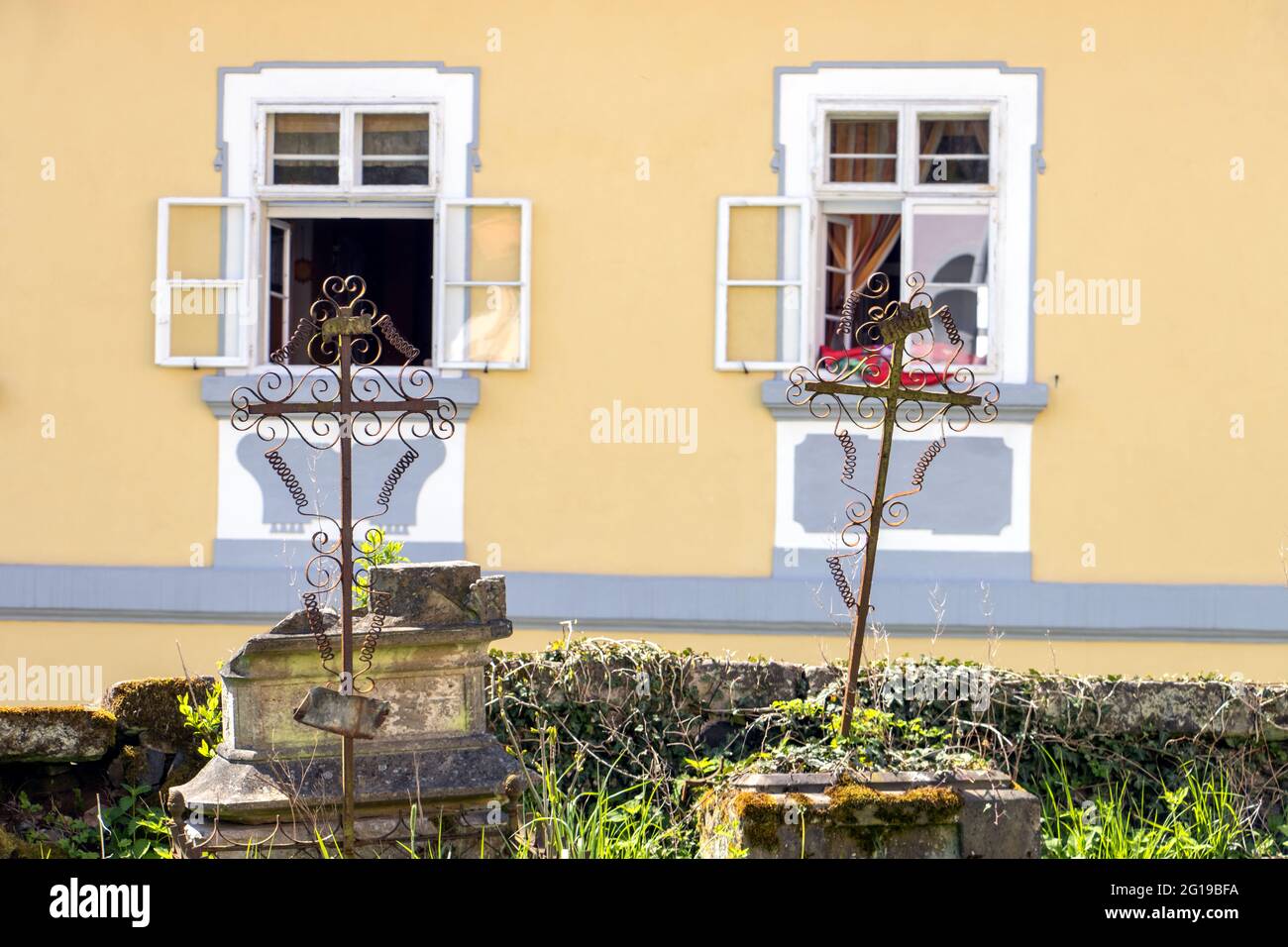 Old crosses on graves under the open windows of a building with a ...