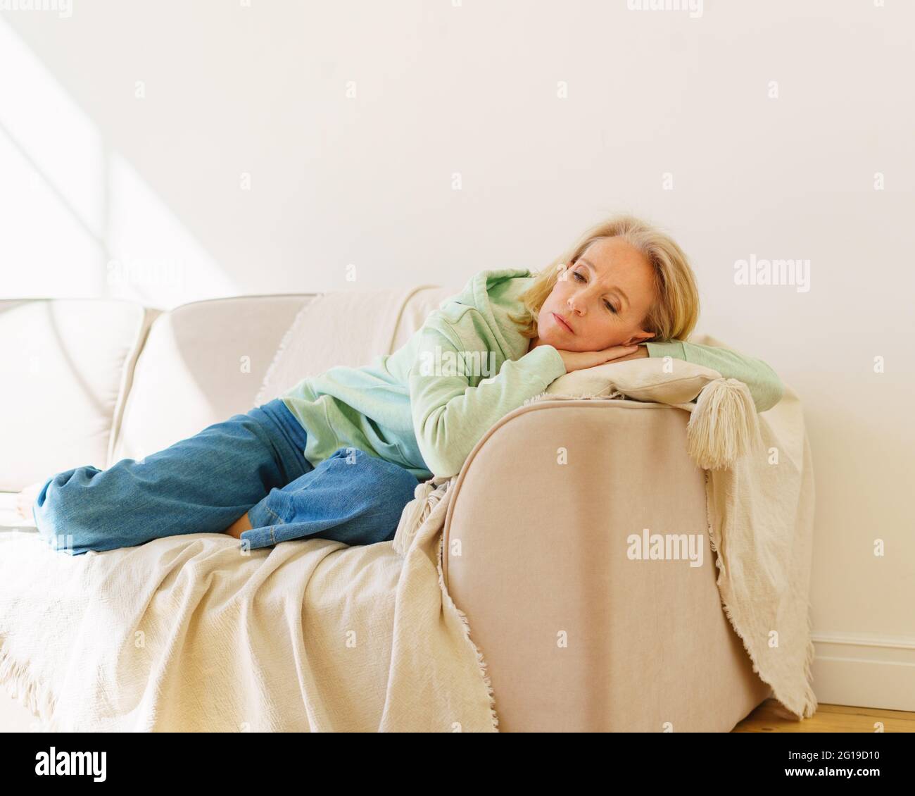 Sad senior 60s woman in casual clothes resting on sofa in living room ...