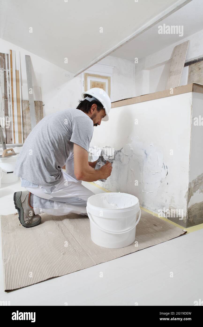 man plasterer construction worker at work, takes plaster from bucket ...