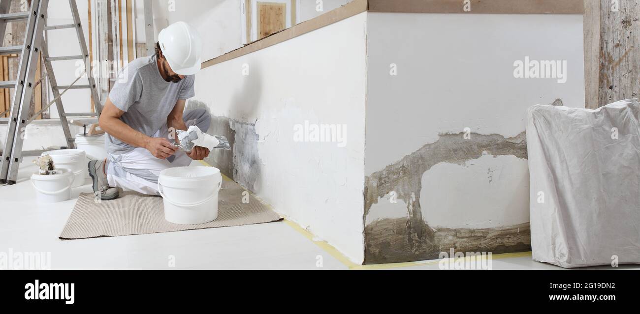 plasterer man at work, take the mortar from the bucket with trowel to ...