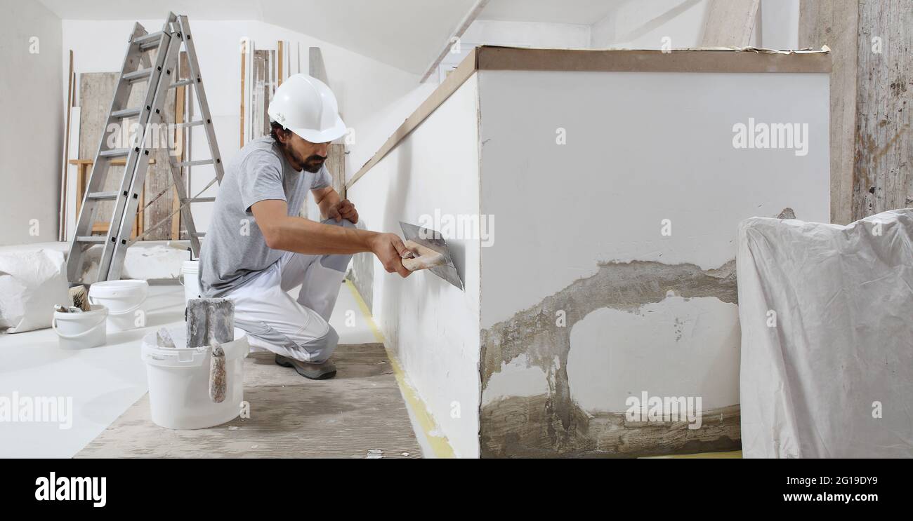 man plasterer construction worker at work, takes plaster from bucket ...