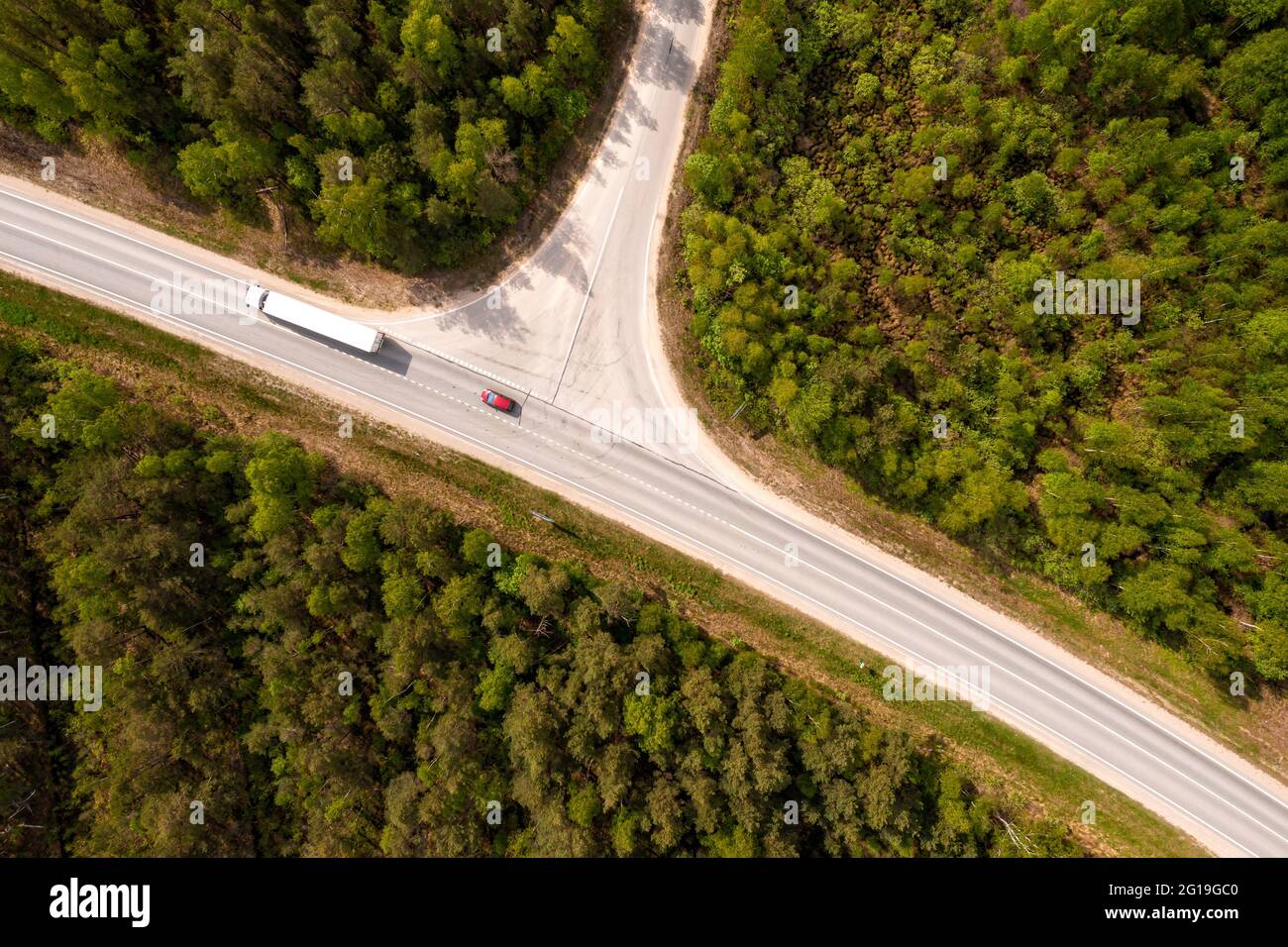 top down view of road intersection in the forest at summer, drone shot ...