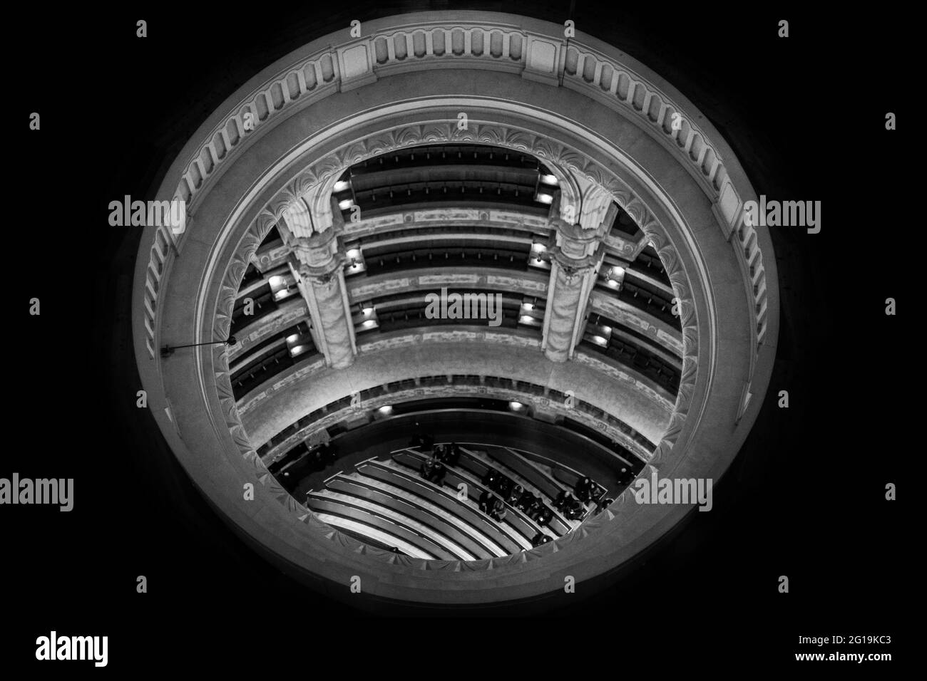 A grayscale top view of a hall from of a building from a round hole ...