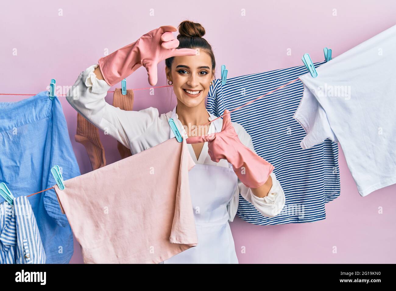 Beautiful brunette young woman washing clothes at clothesline smiling ...