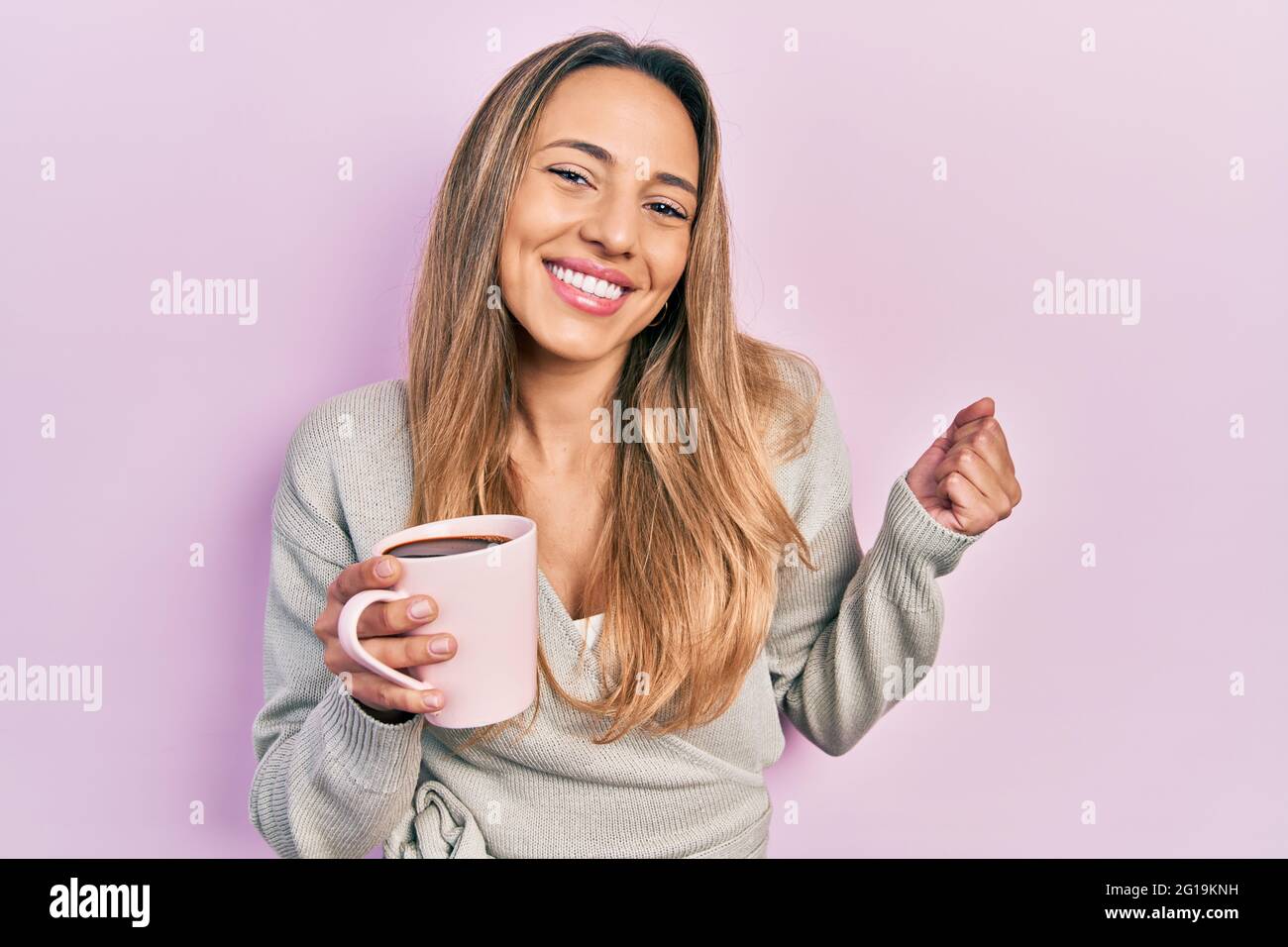 Beautiful hispanic woman drinking a cup coffee screaming proud ...
