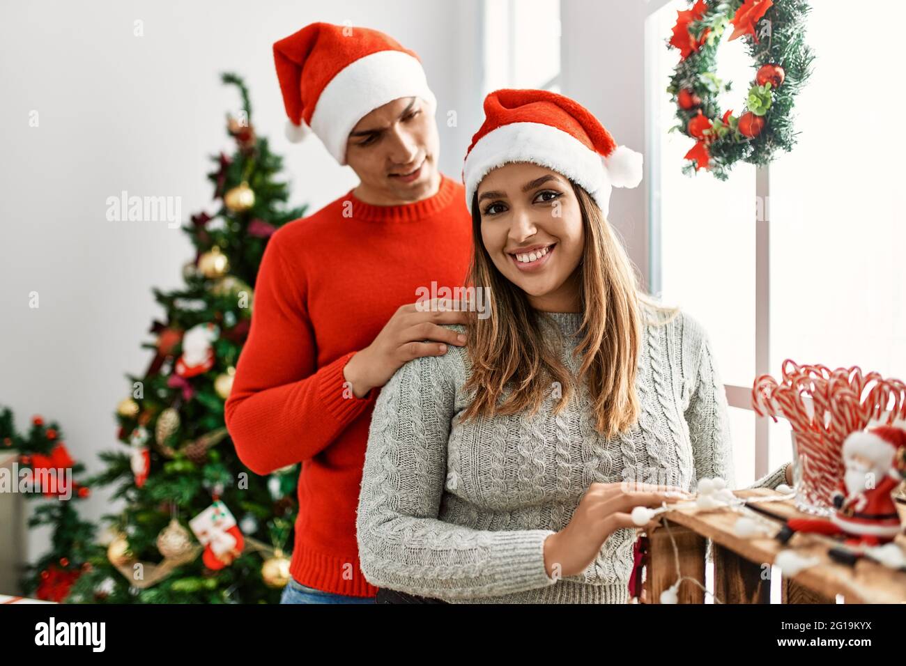 Young couple smiling happy wearing christmas hat. Standing with smile ...