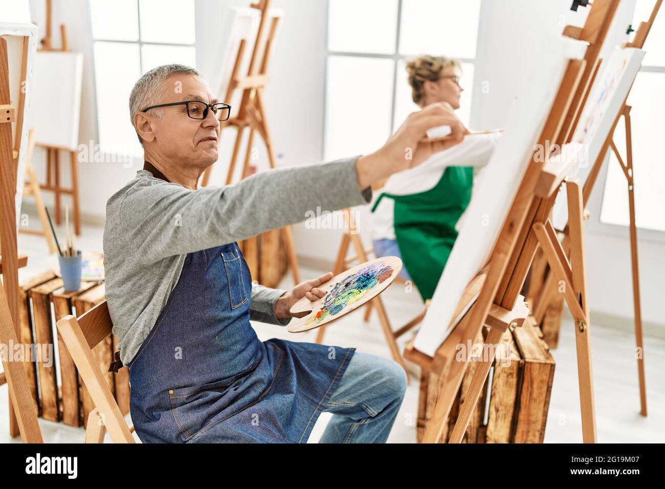 Two middle age artist concentrated painting at art studio Stock Photo ...