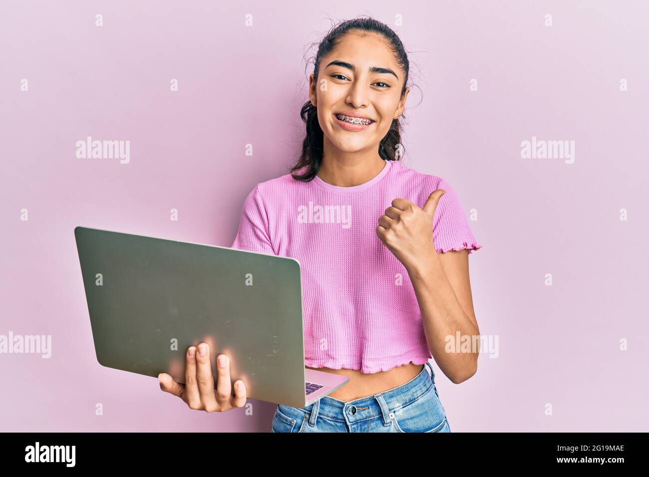 Hispanic teenager girl with dental braces holding and using computer ...