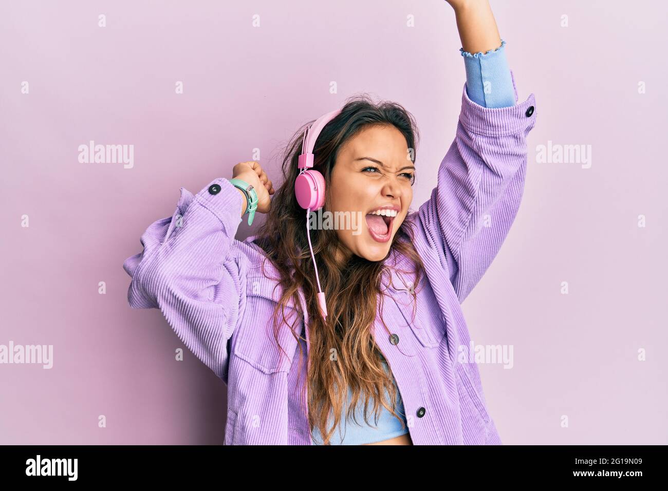 Young hispanic girl dancing and listening to music using headphones ...