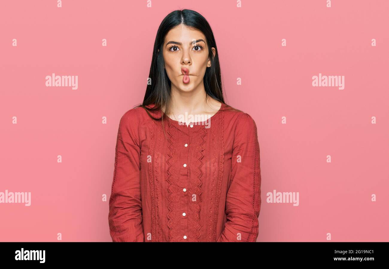 Young hispanic woman wearing casual clothes making fish face with lips ...