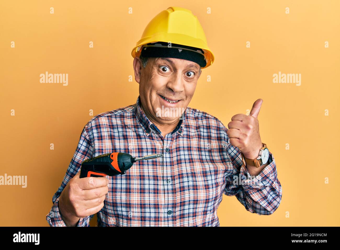 Handsome senior man with grey hair holding screwdriver wearing hardhat ...