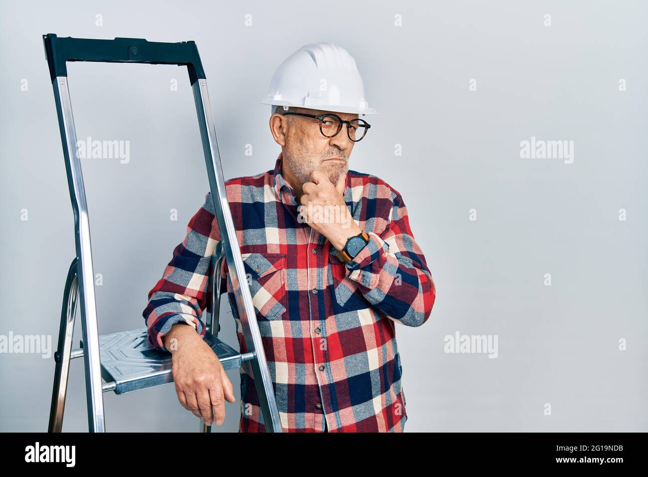 Handsome mature handyman close to construction stairs wearing hardhat ...