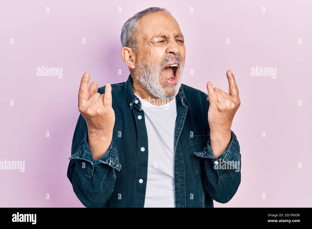 Handsome senior man with beard doing rock gesture angry and mad ...