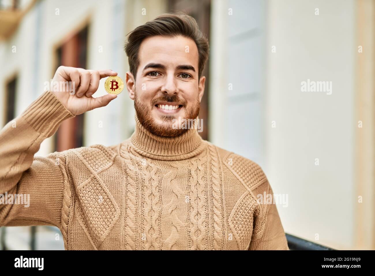 Young caucasian man smiling happy holding bitcoin at the city Stock ...