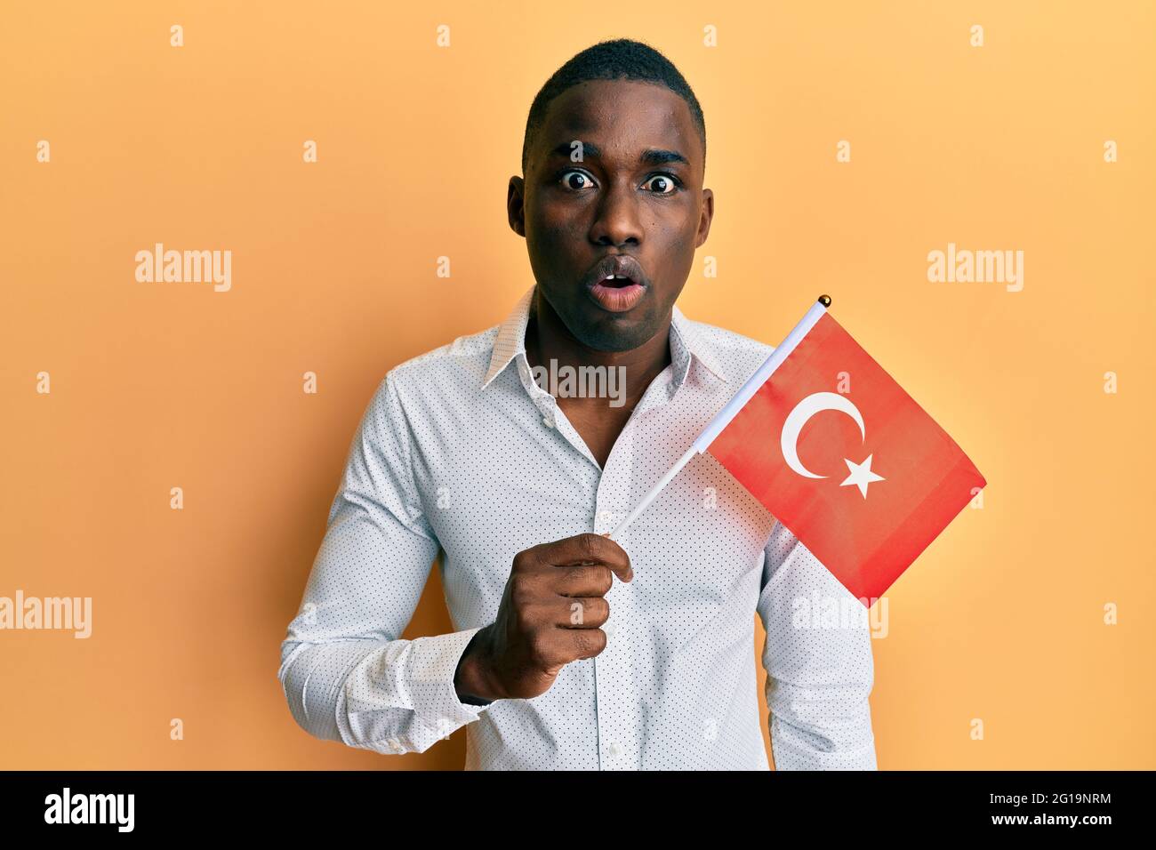 Young african american man holding turkey flag scared and amazed with ...