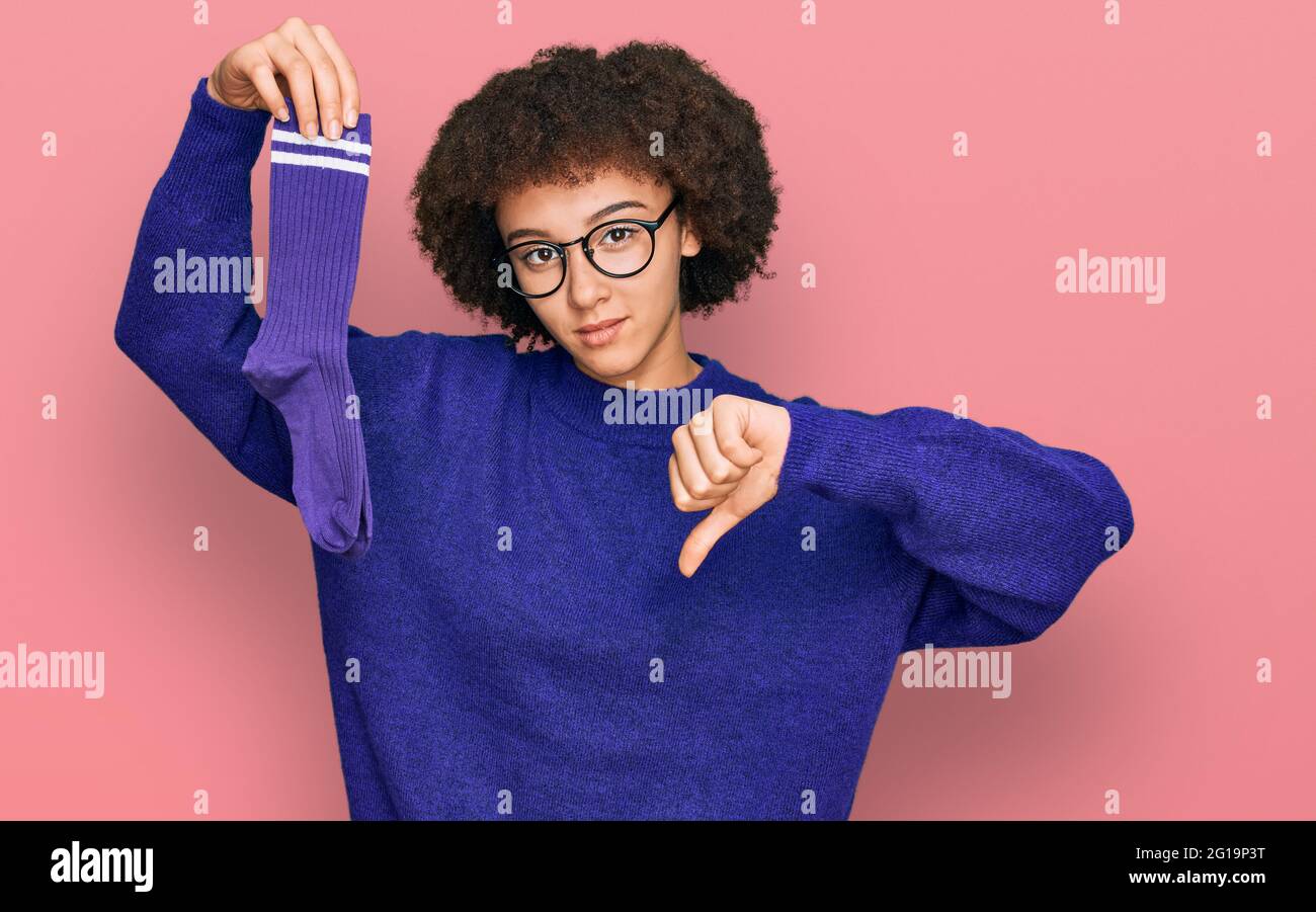 Young hispanic girl holding sporty sock with angry face, negative sign ...