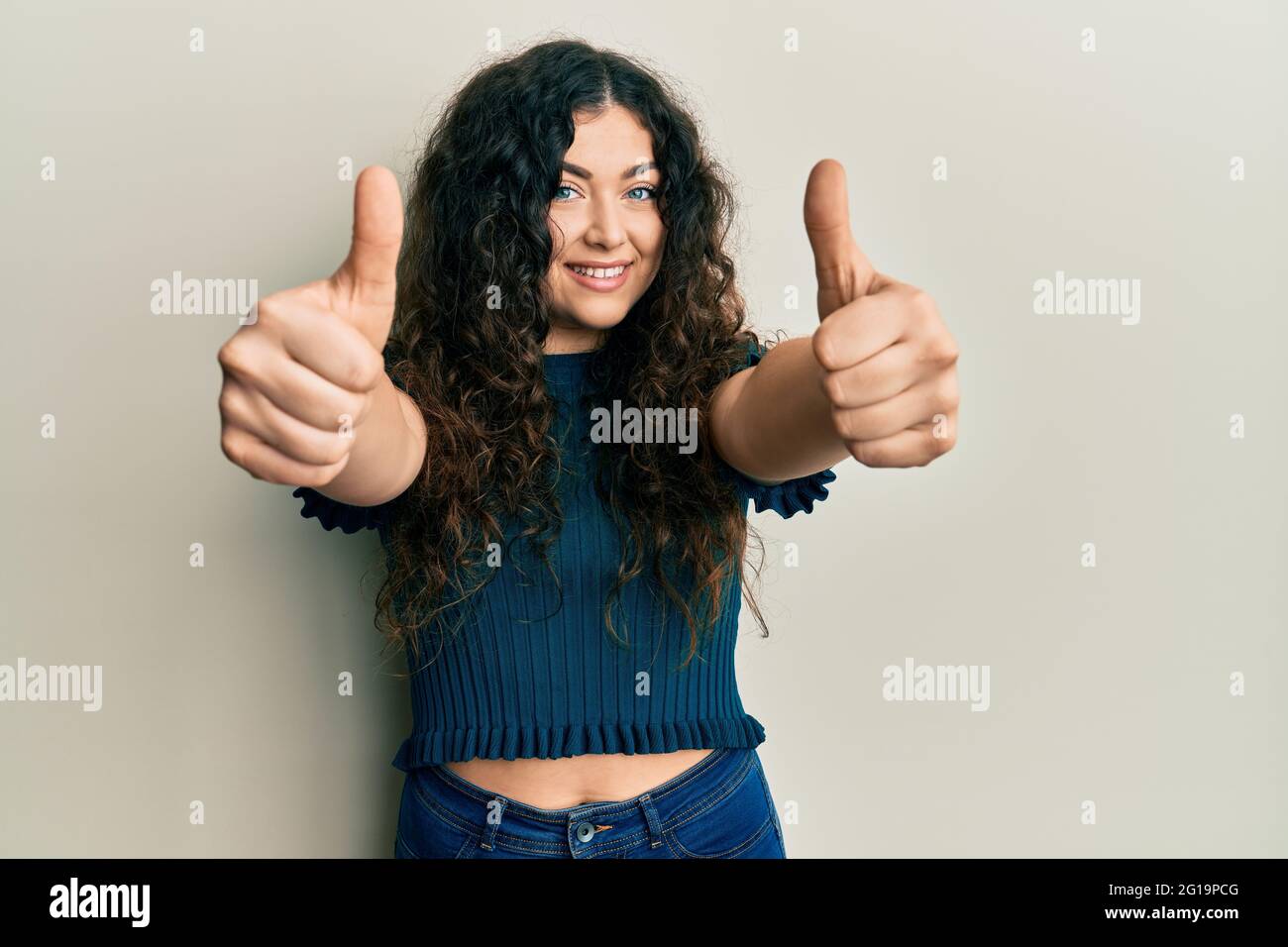 Young brunette woman with curly hair wearing casual clothes approving ...
