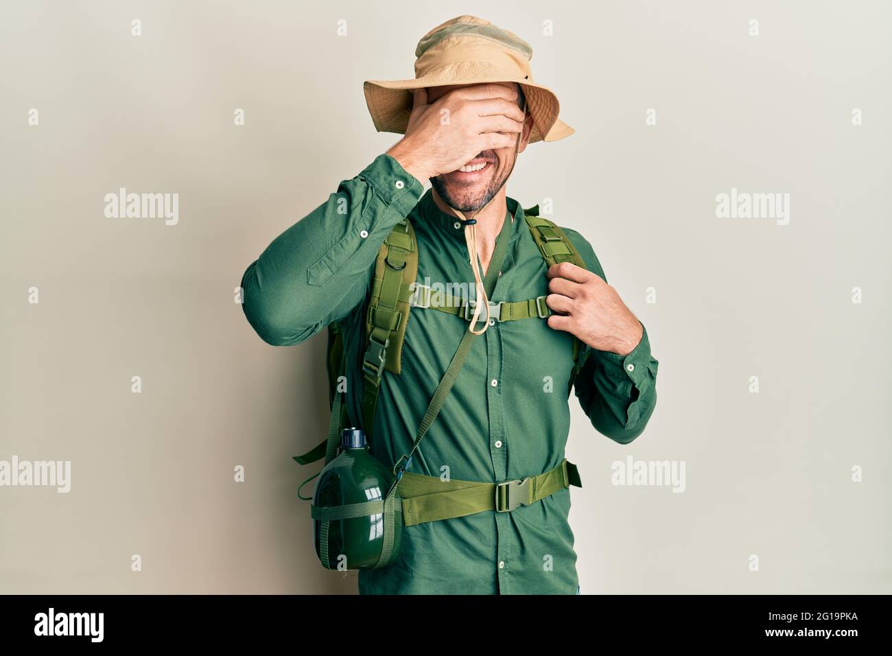 Handsome man with beard wearing explorer hat and backpack smiling and ...