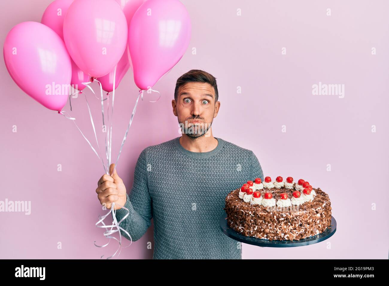 Handsome man with beard celebrating birthday with cake holding balloons ...