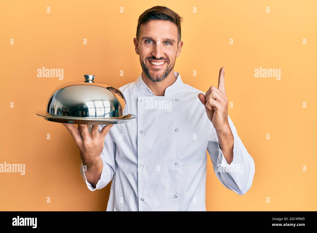 Handsome man with beard wearing chef uniform holding silver tray ...