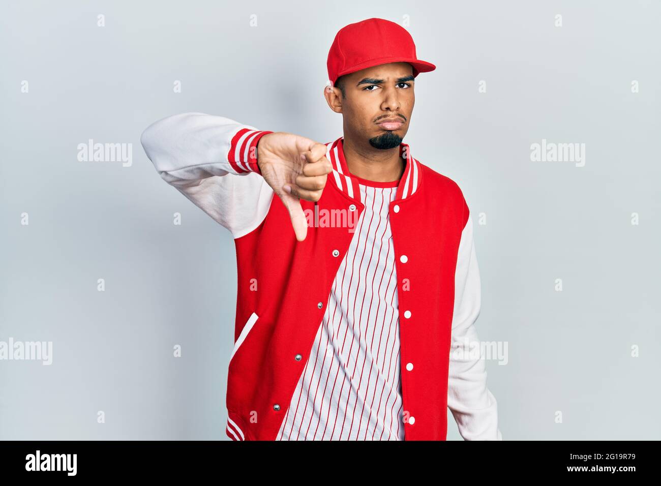 Young african american man wearing baseball uniform looking unhappy and ...