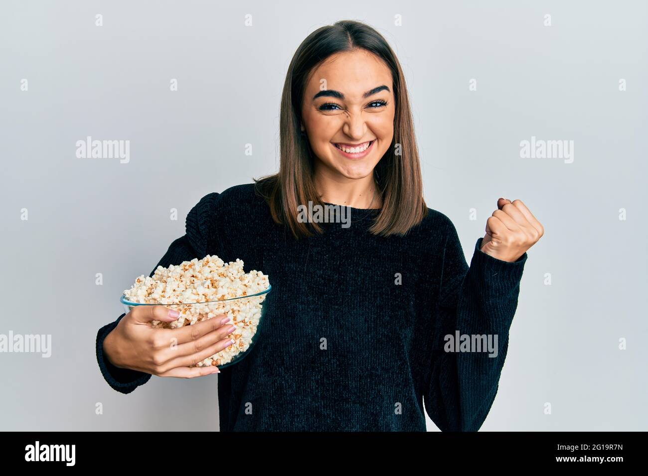 Young brunette girl eating popcorn screaming proud, celebrating victory ...