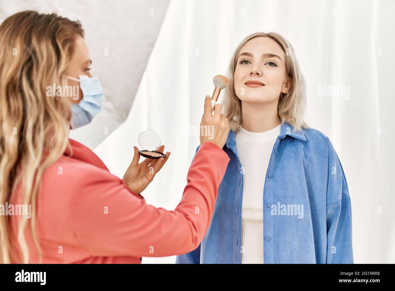 Stylist woman applying make up to beautiful caucasian model at photo ...